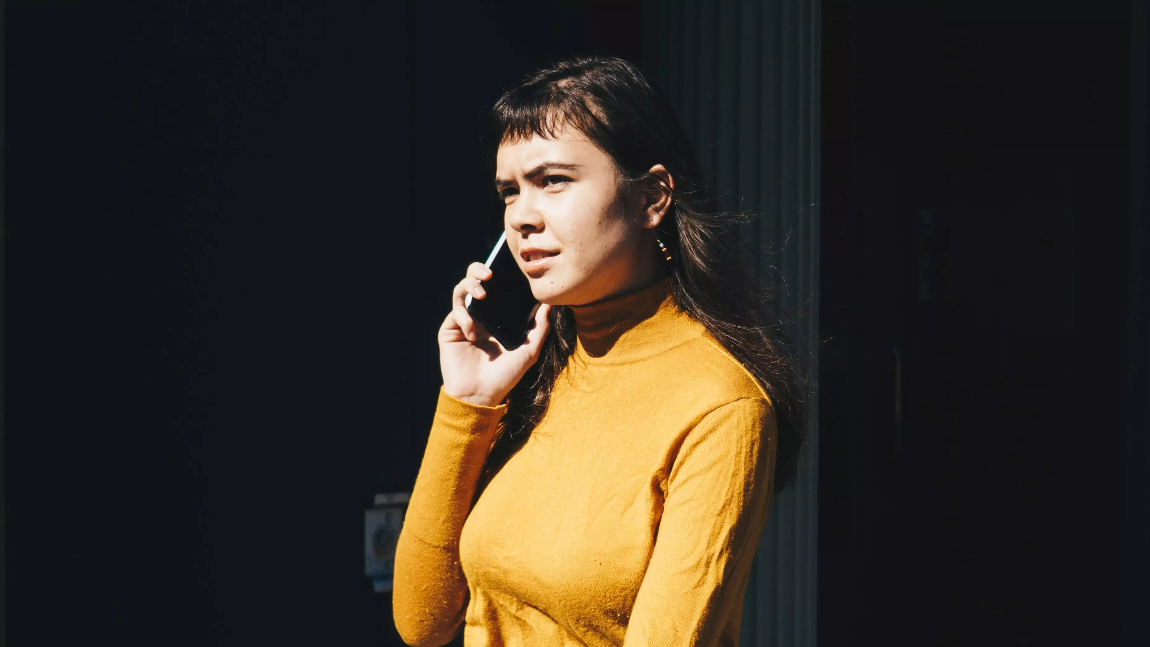 Unha muller cunha camisa amarela falando por teléfono.