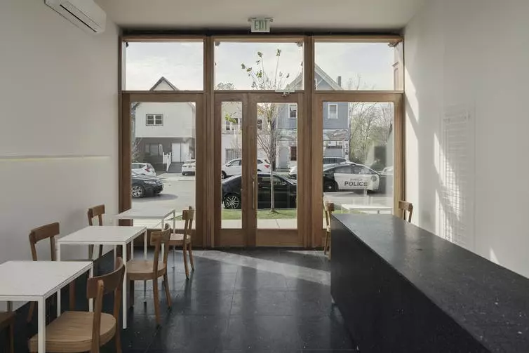 หน้าต่างสูงจากพื้นจรดพื้นและโต๊ะขนาดกะทัดรัดเป็นจุดเด่นของร้านกาแฟ